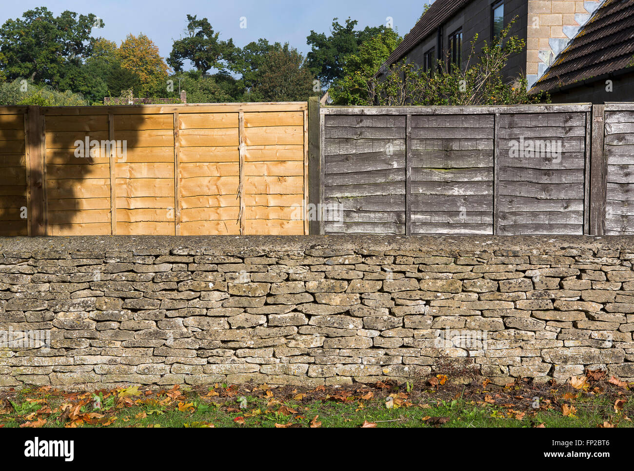 Residential fence with dry stone wall split between new and old wood ...