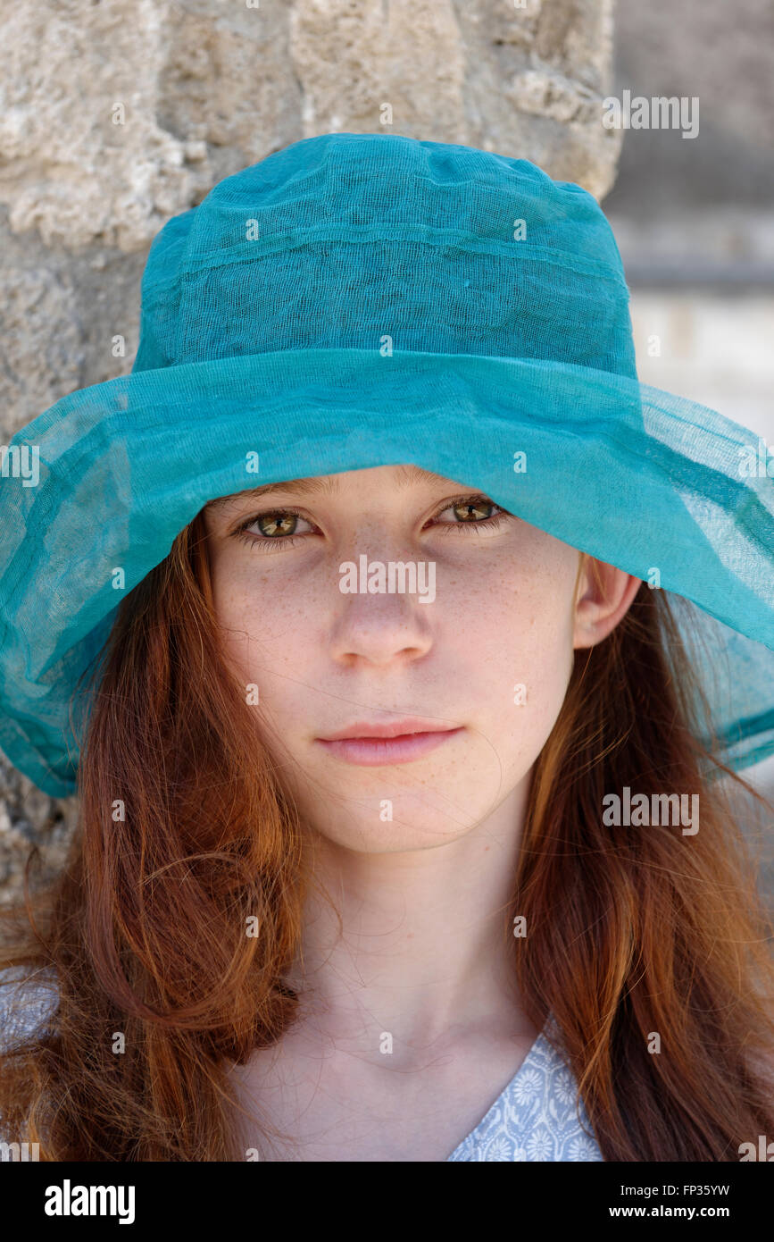 Red-haired girl with a turquoise sun hat looking seriously, portrait ...