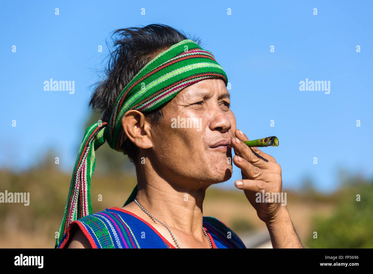 Man in traditional costume smoking cigar, Phnong tribe, ethnic minority ...