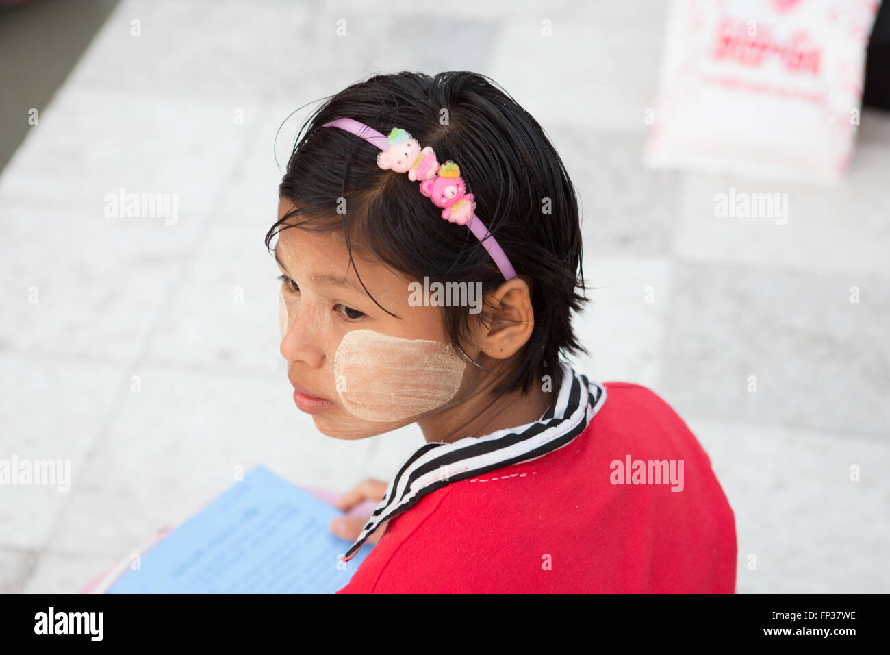 Burmese girl wearing headband at Shwedagon Pagoda with Thanaka on face ...