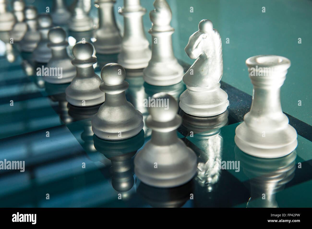 Pieces of a glass or hard plastic chess set glow as they are backlit by ...