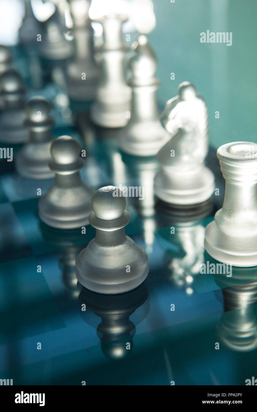 Pieces of a glass or hard plastic chess set glow as they are backlit by ...