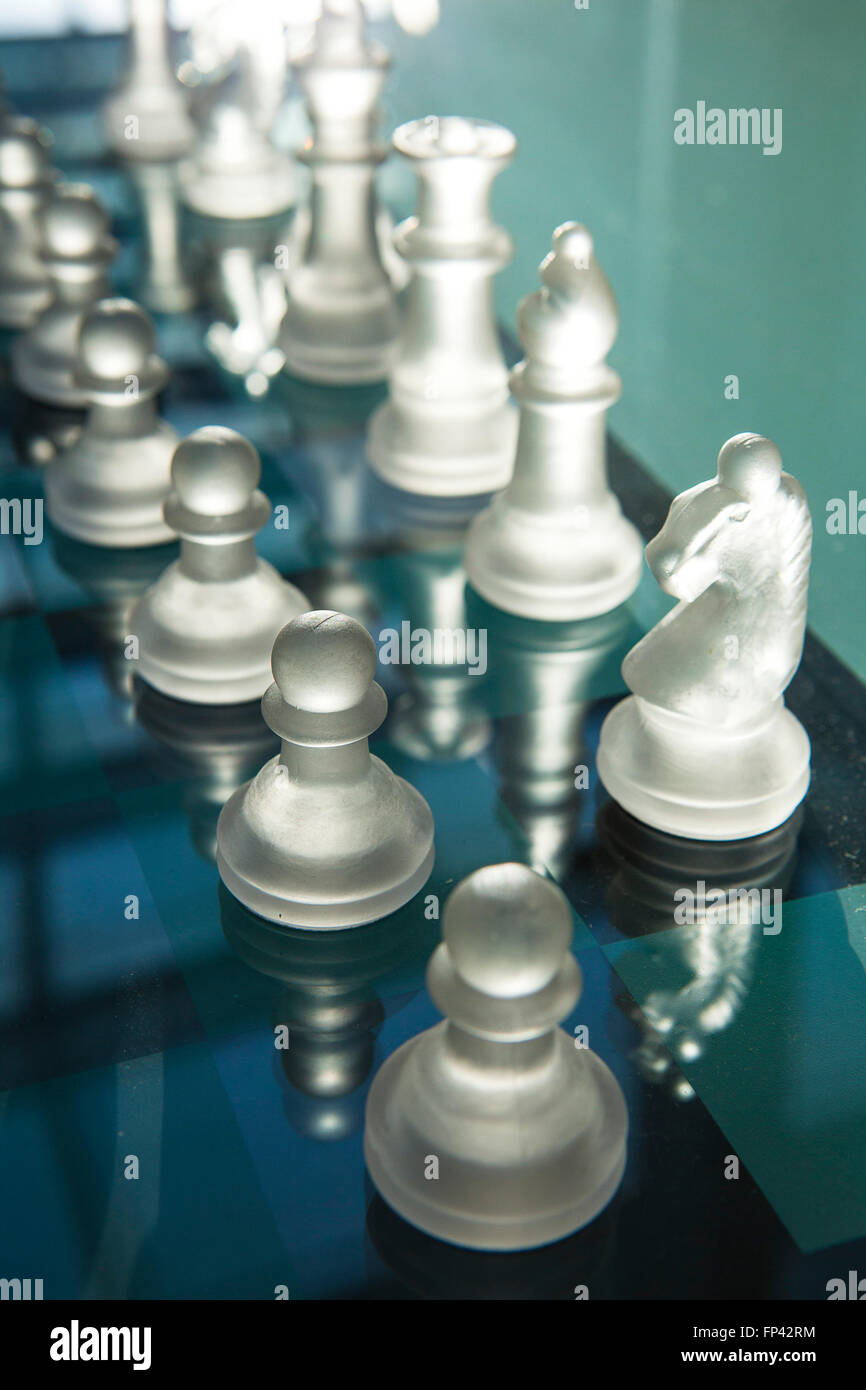 Pieces of a glass or hard plastic chess set glow as they are backlit by ...