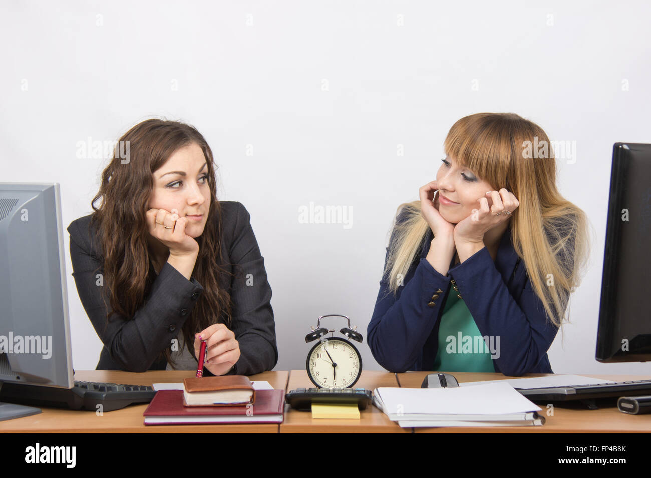 Two bored office worker waiting for the end of the day and look at each ...