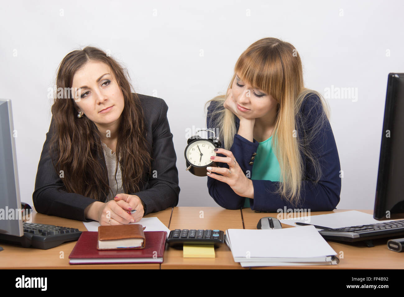 Two tired women in the office awaiting the end of the working day Stock ...