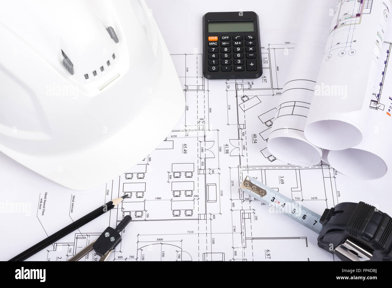 Architecture plan and rolls of blueprints with meter and helmet ...