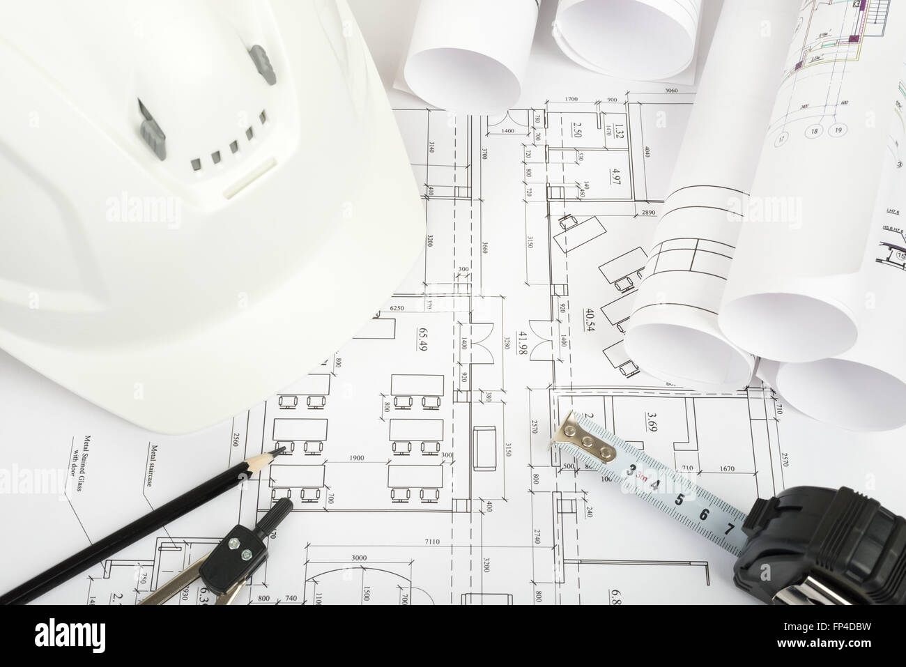 Architecture plan and rolls of blueprints with meter and helmet ...