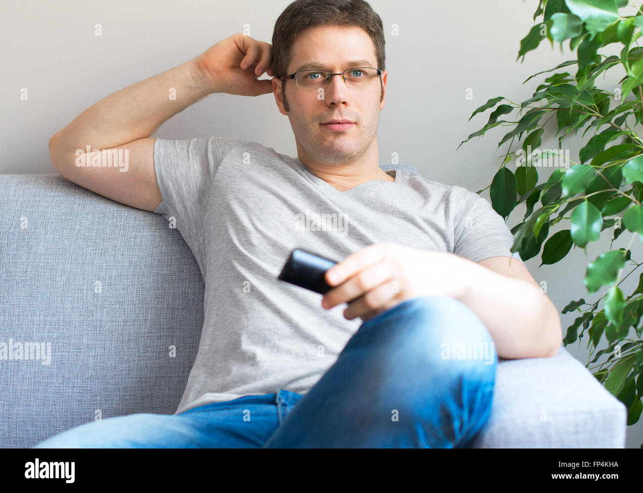 Man relaxing on the sofa with tv remote control Stock Photo - Alamy