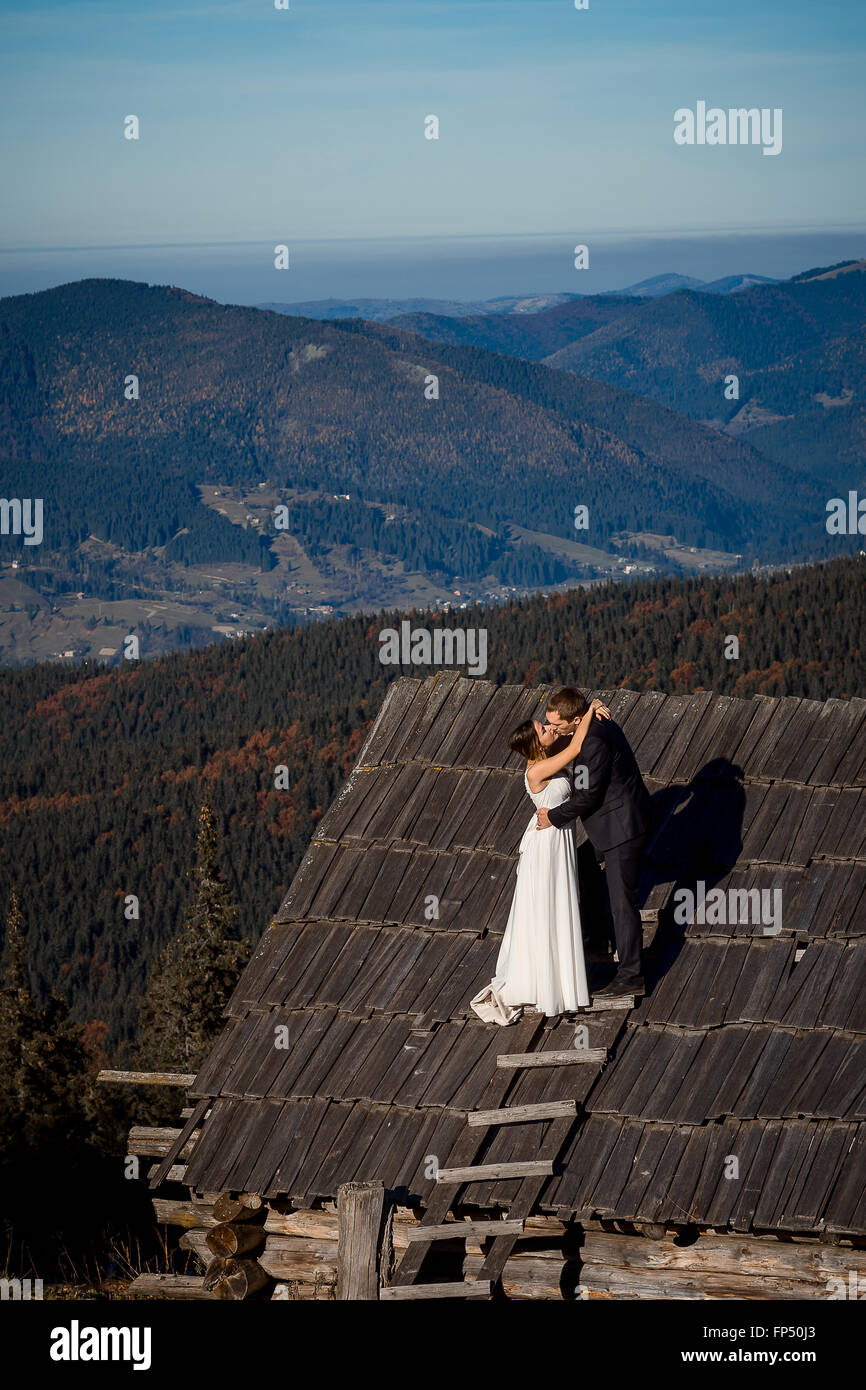 Charming wedding couple kissing on the roof of country house. Amazing ...