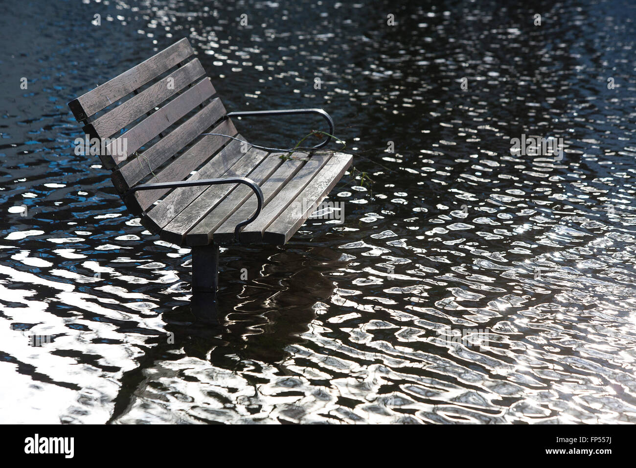 A wooden park bench in a flooded field indicating the change in wether ...