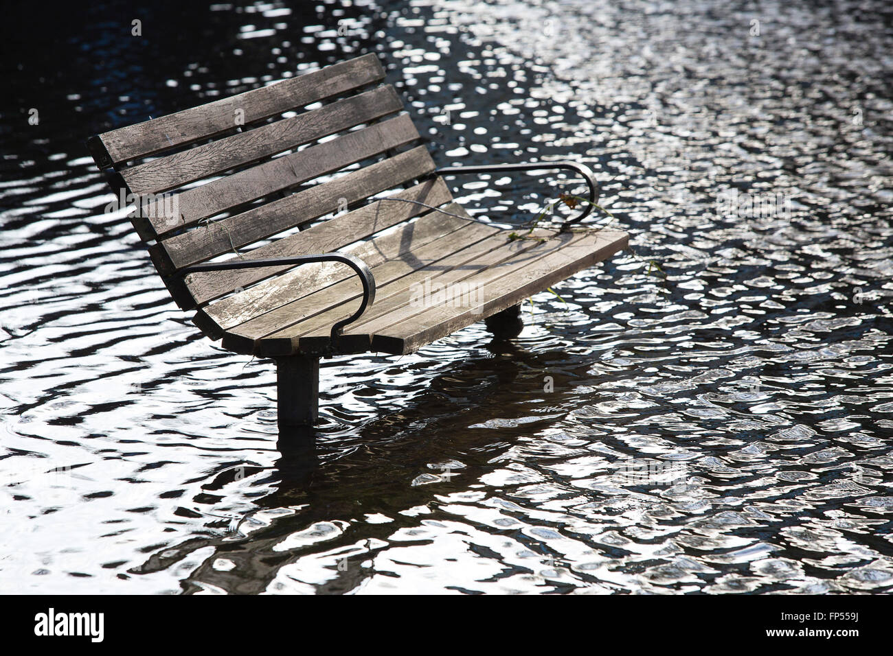 A wooden park bench in a flooded field indicating the change in wether ...