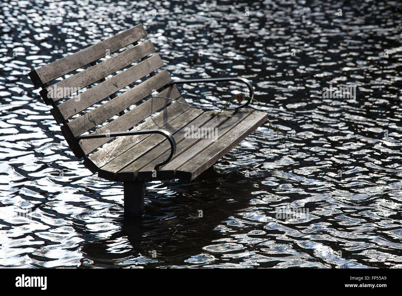 A wooden park bench in a flooded field indicating the change in wether ...