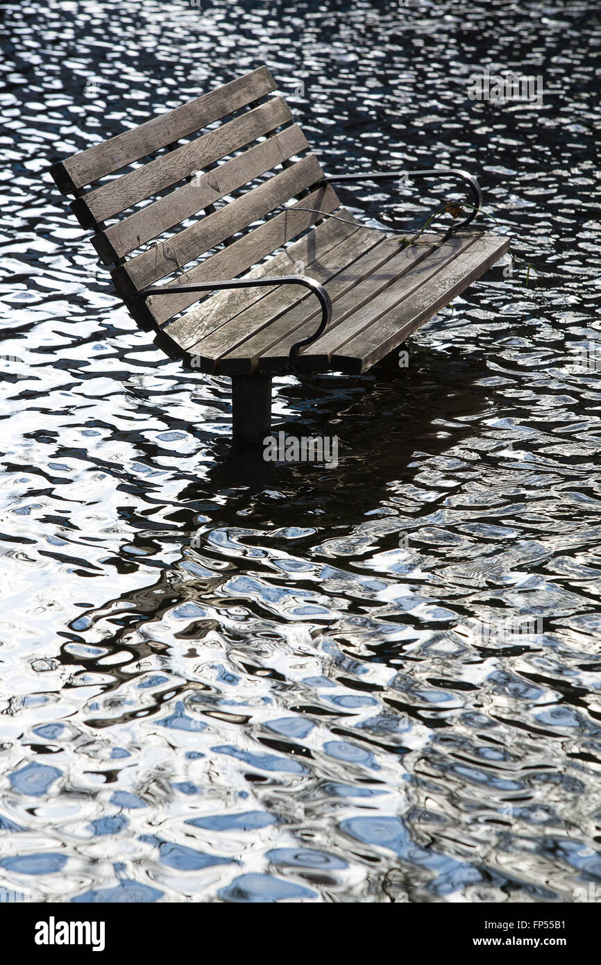 A wooden park bench in a flooded field indicating the change in wether ...