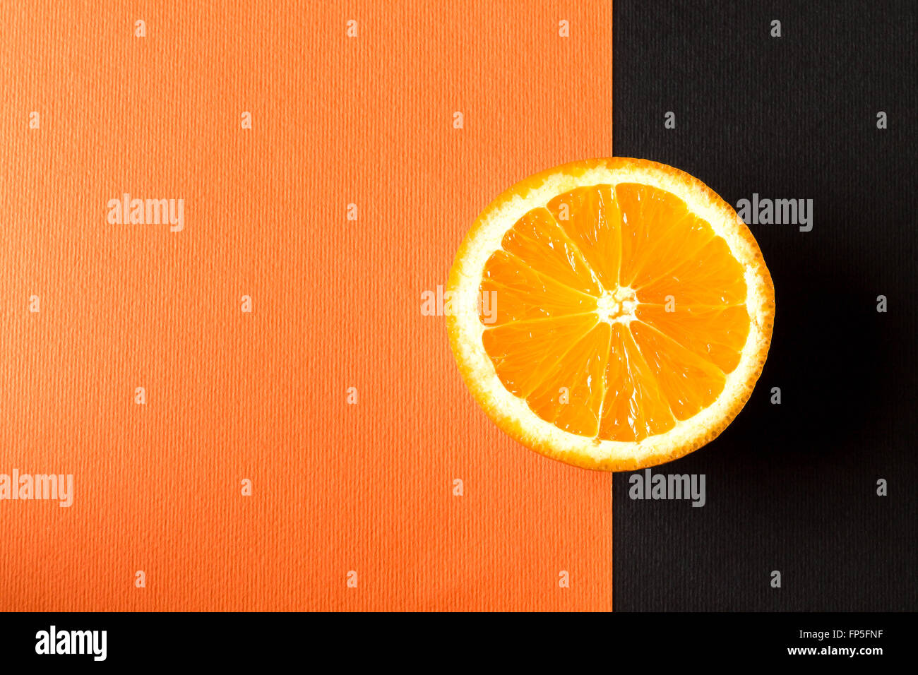 Orange fruit on black and orange paper background. Plenty of copy space ...