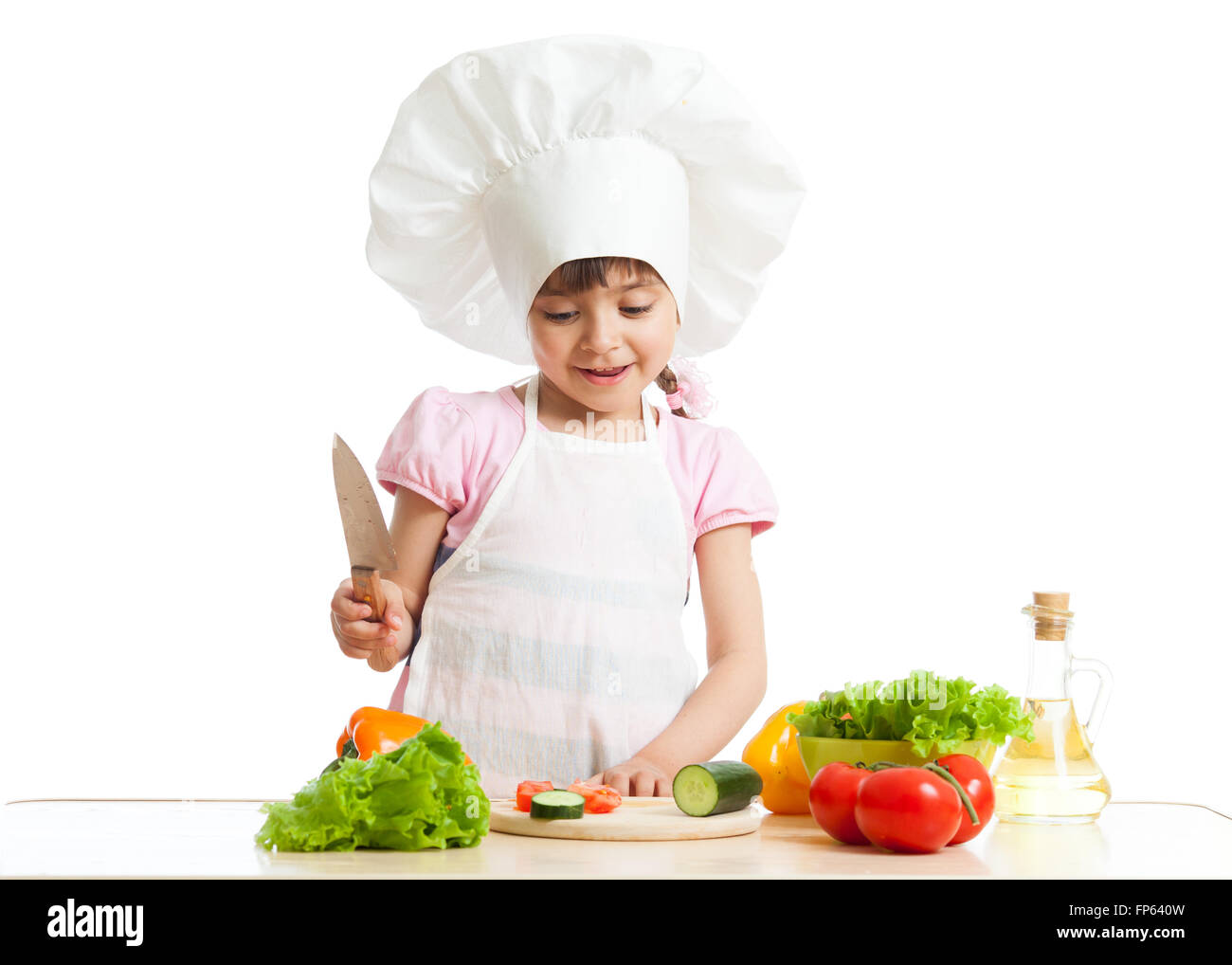 Child girl is cutting vegetables for salad using kitchen knife ...