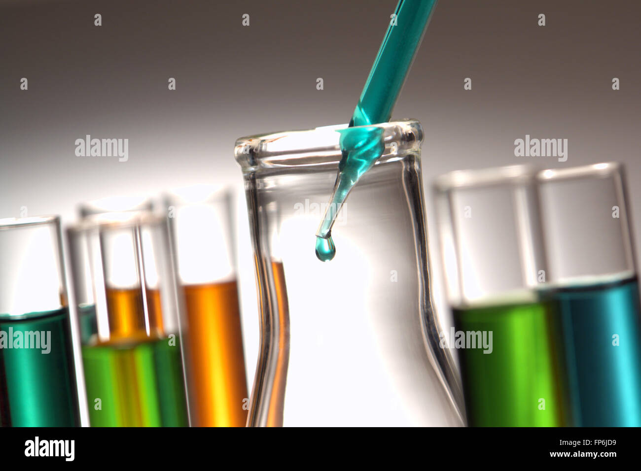 Laboratory pipette with drop of blue chemical solution inside a glass ...