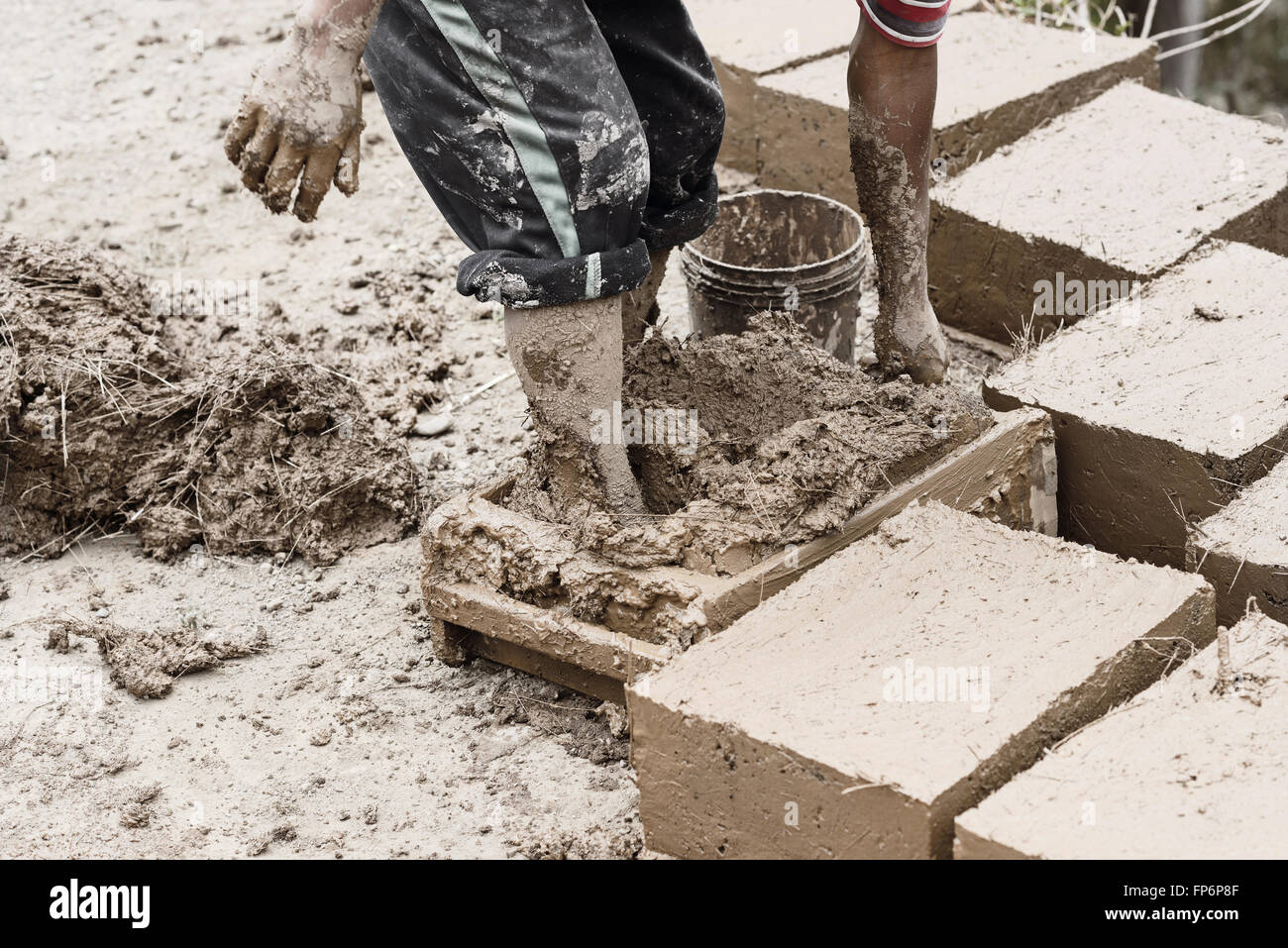 Boy making traditional adobe mud bricks to build his own house in Paru ...