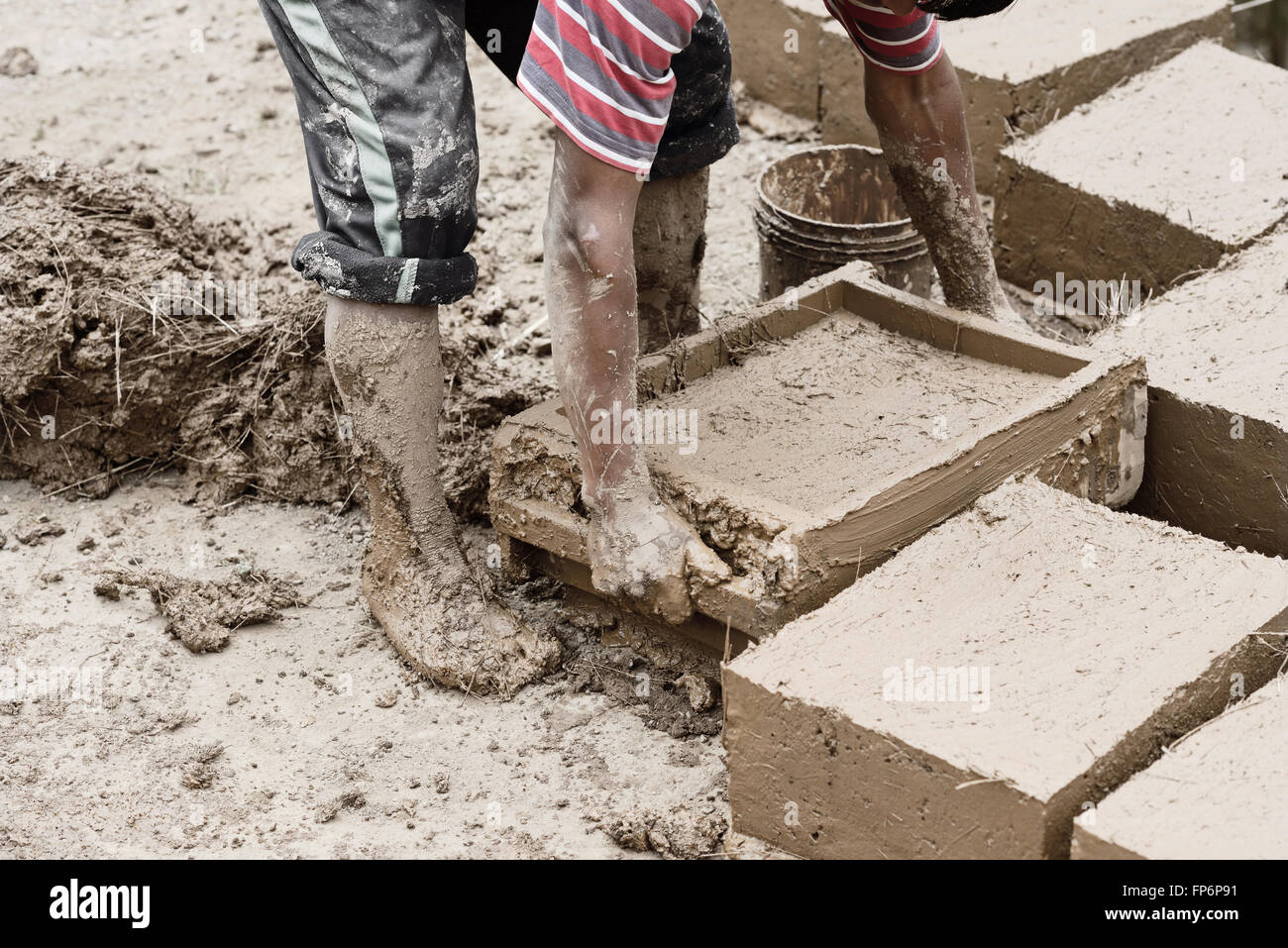 Boy making traditional adobe mud bricks to build his own house in Paru ...