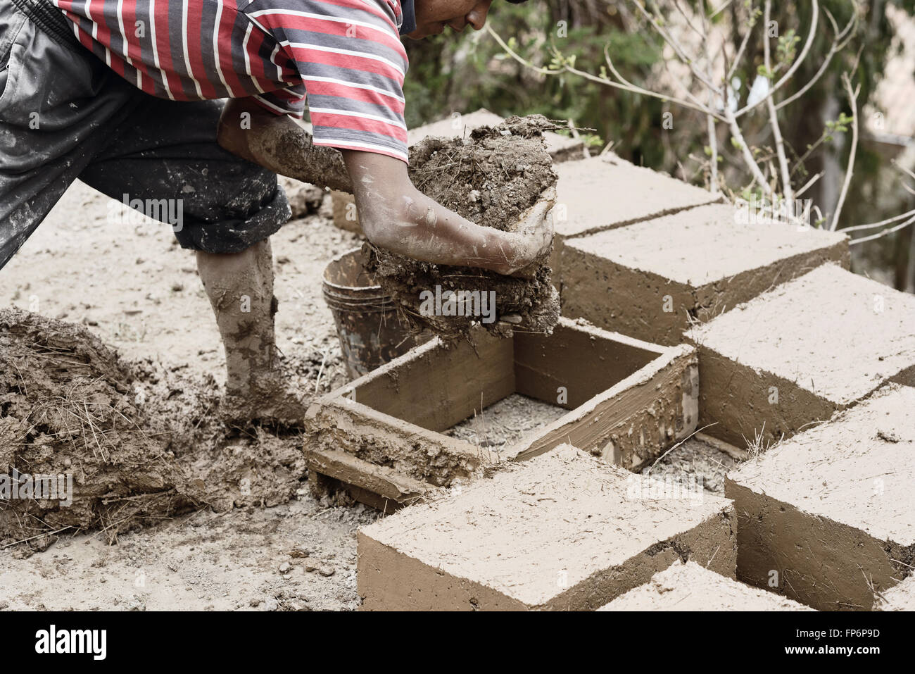 Boy making traditional adobe mud bricks to build his own house in Paru ...