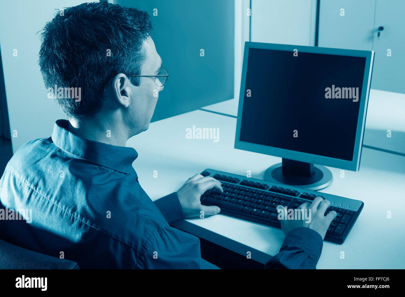 Man and computer in an office in blue tone. Horizontal Stock Photo - Alamy