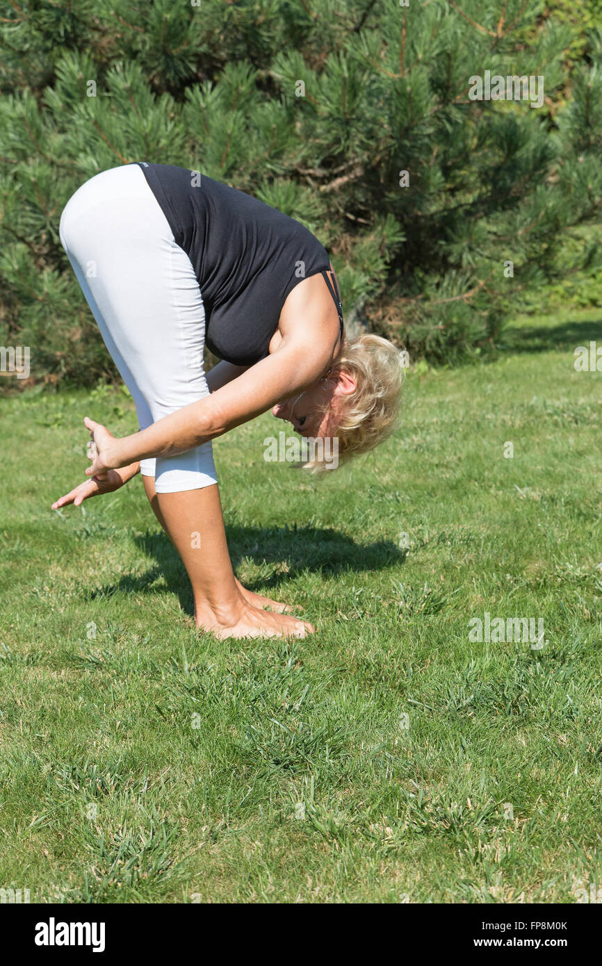 Side view of flexible senior woman is forward bending outdoors Stock ...