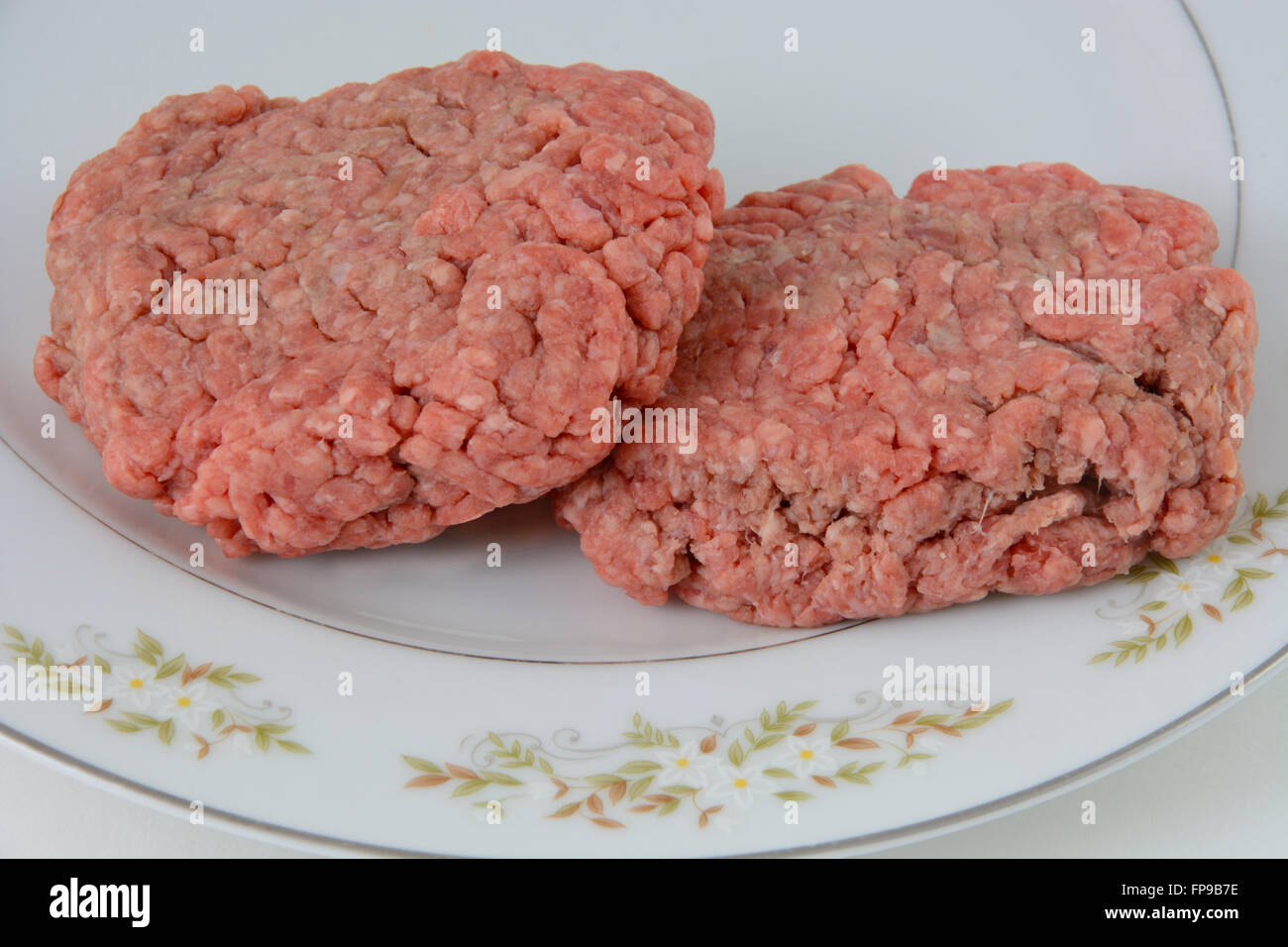Two raw uncooked hamburger patties on plate in preparation of cooking ...