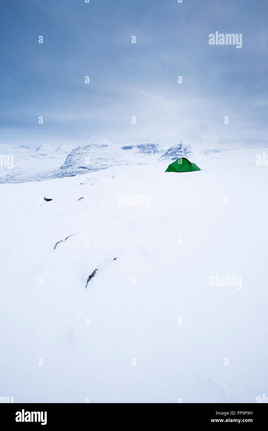 A tent pitched in the snow of the Torridon hills in winter with Beinn ...