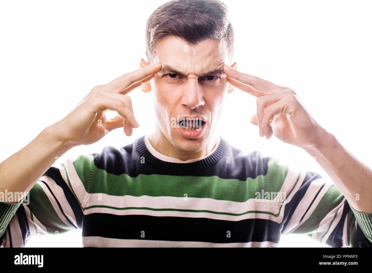 Portrait of a smart serious young man standing against white background ...