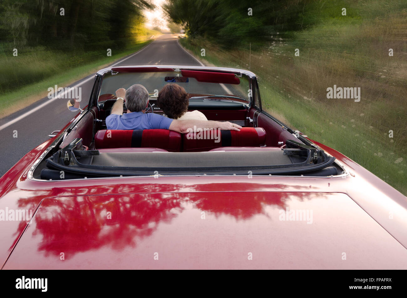 A middle-aged couple snuggle together as they zoom down a county road ...