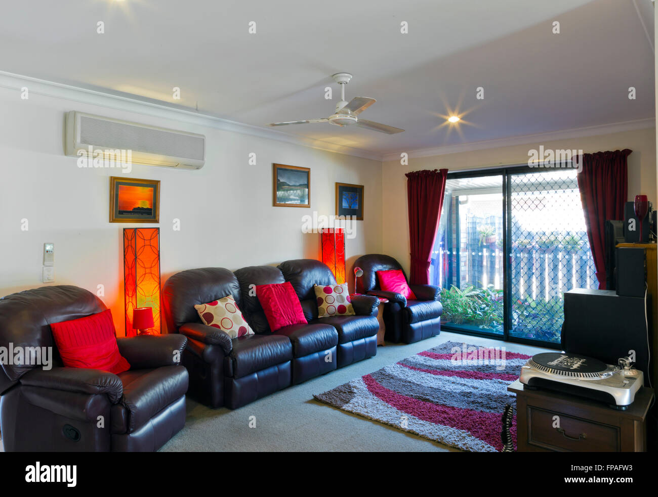 Lounge room with red theme showing lamps, cushions, air conditioner ...