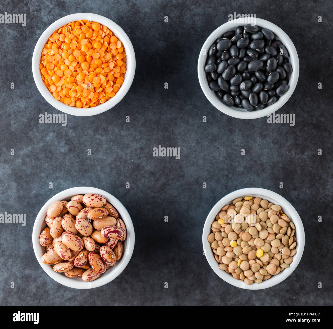 Red and brown lentils, heirloom beans, and black turtle beans on dark ...