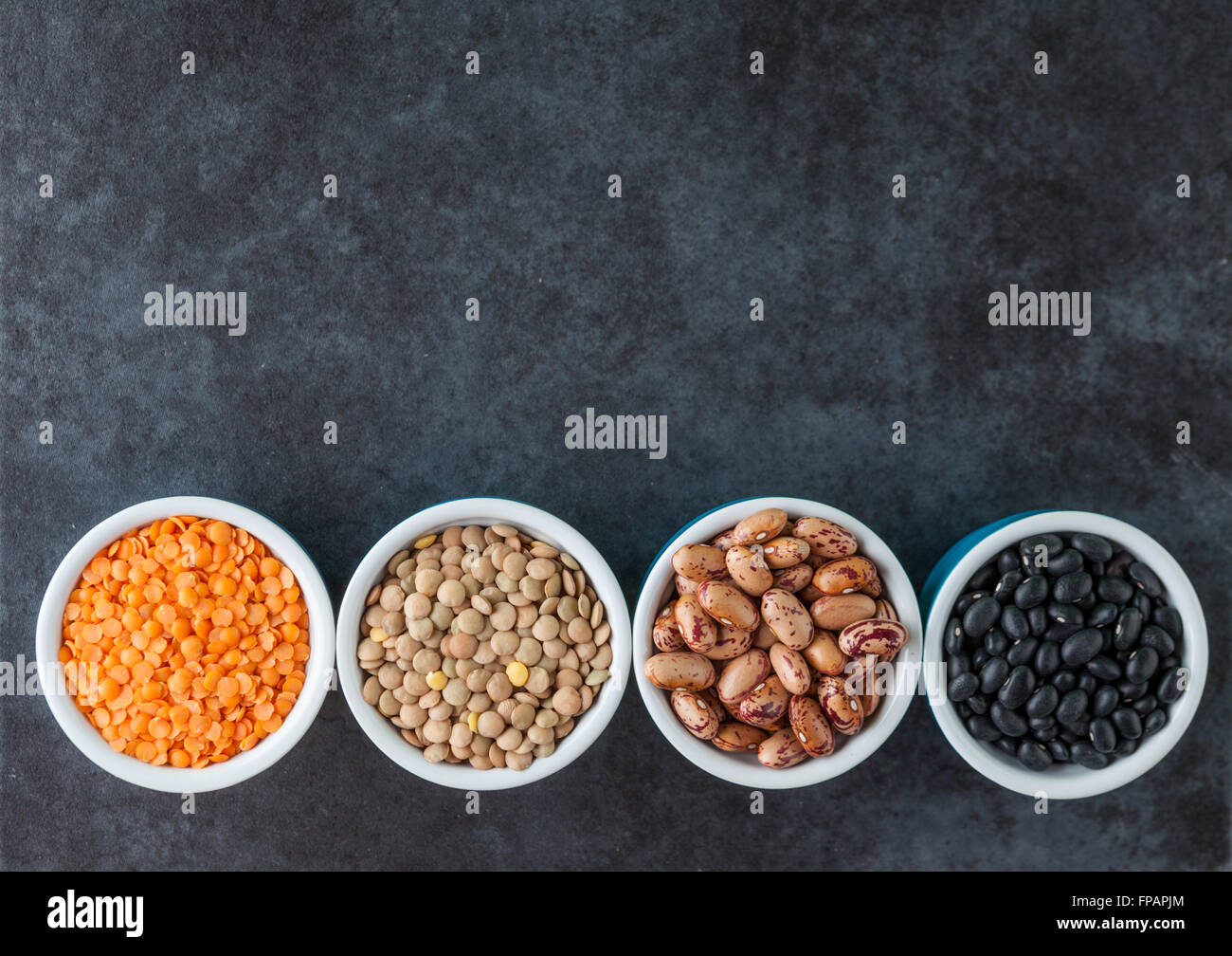 Red and brown lentils, heirloom beans, and black turtle beans on dark ...