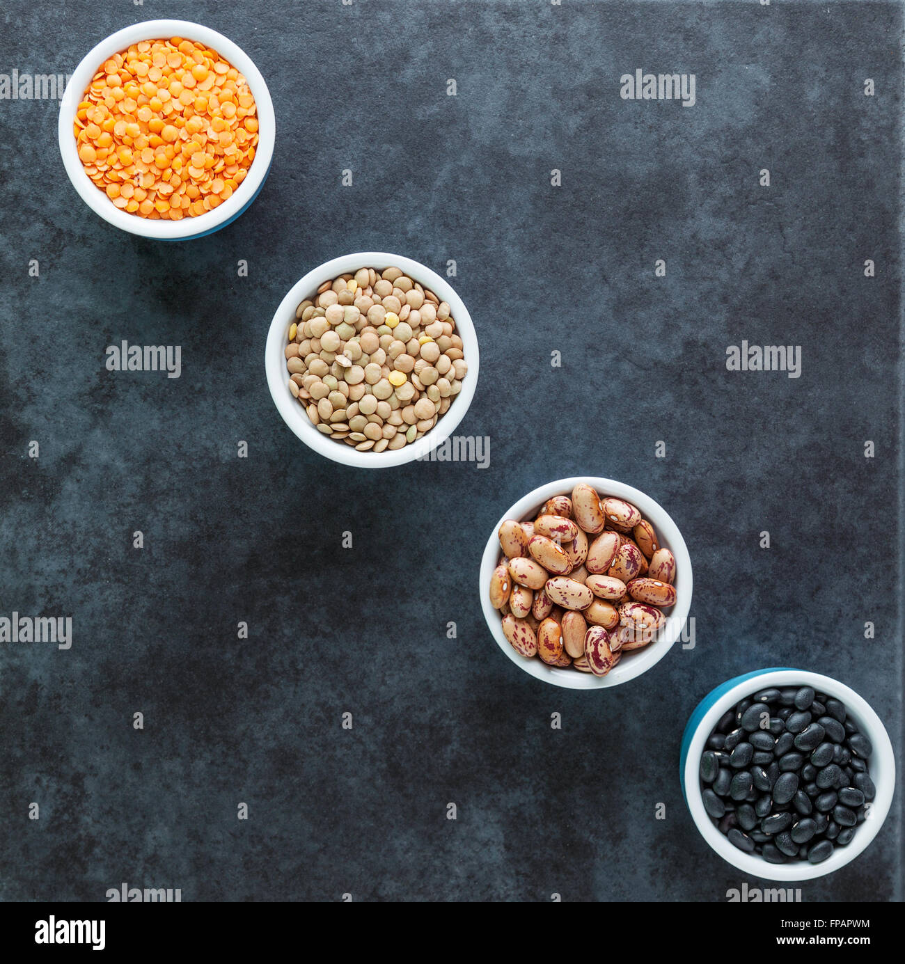 Red and brown lentils, heirloom beans, and black turtle beans on dark ...