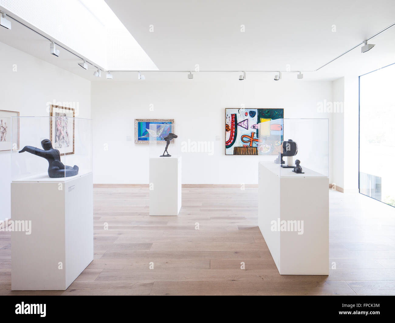 A viewing room in an art gallery with art on the walls, figurines in ...
