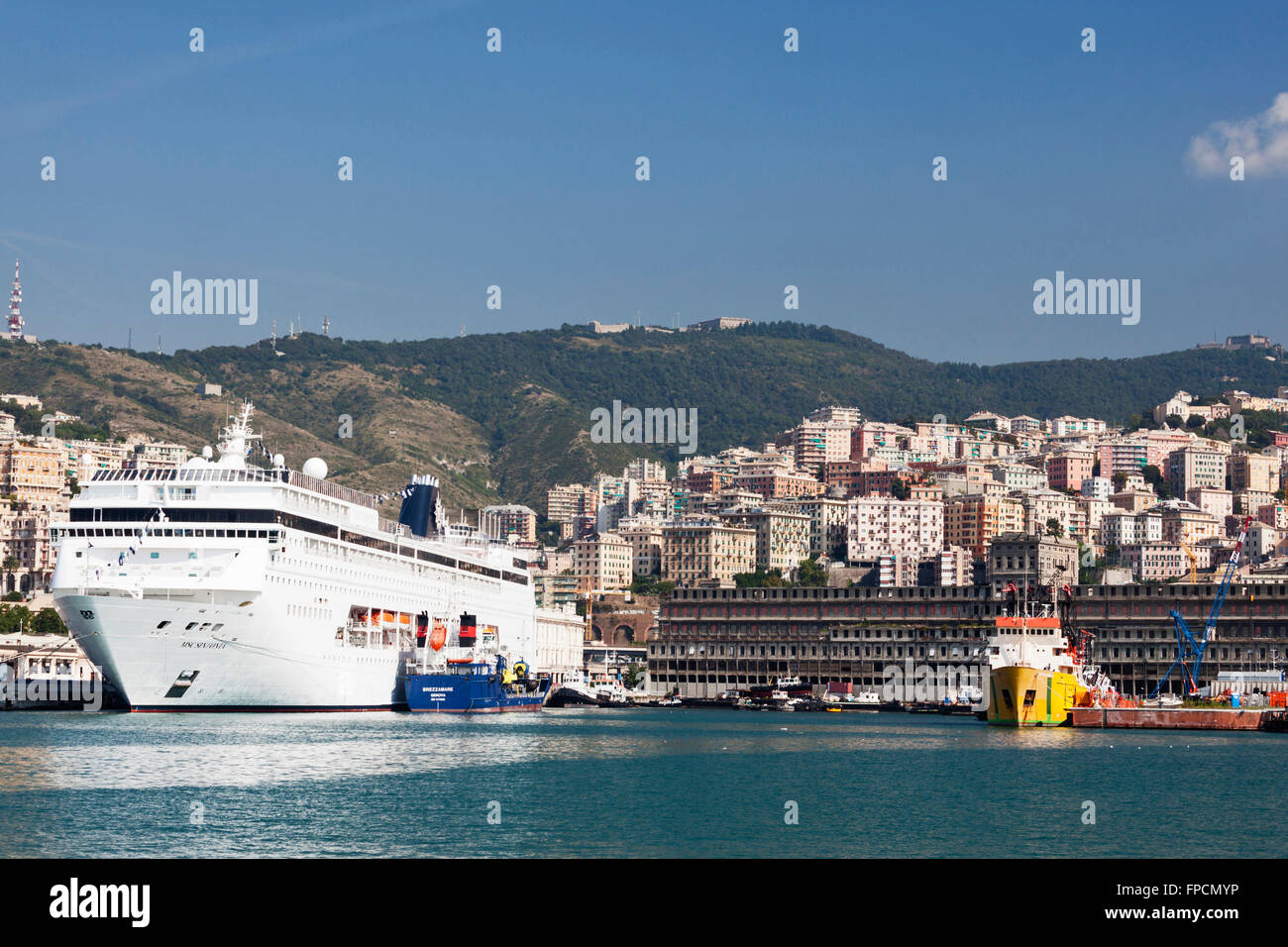 A ship in the port of Genoa. With the city and mountains in the ...