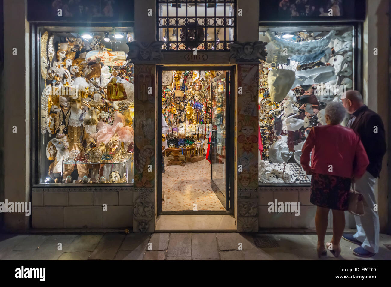 An elder couple looking at the illuminated window of a store selling ...