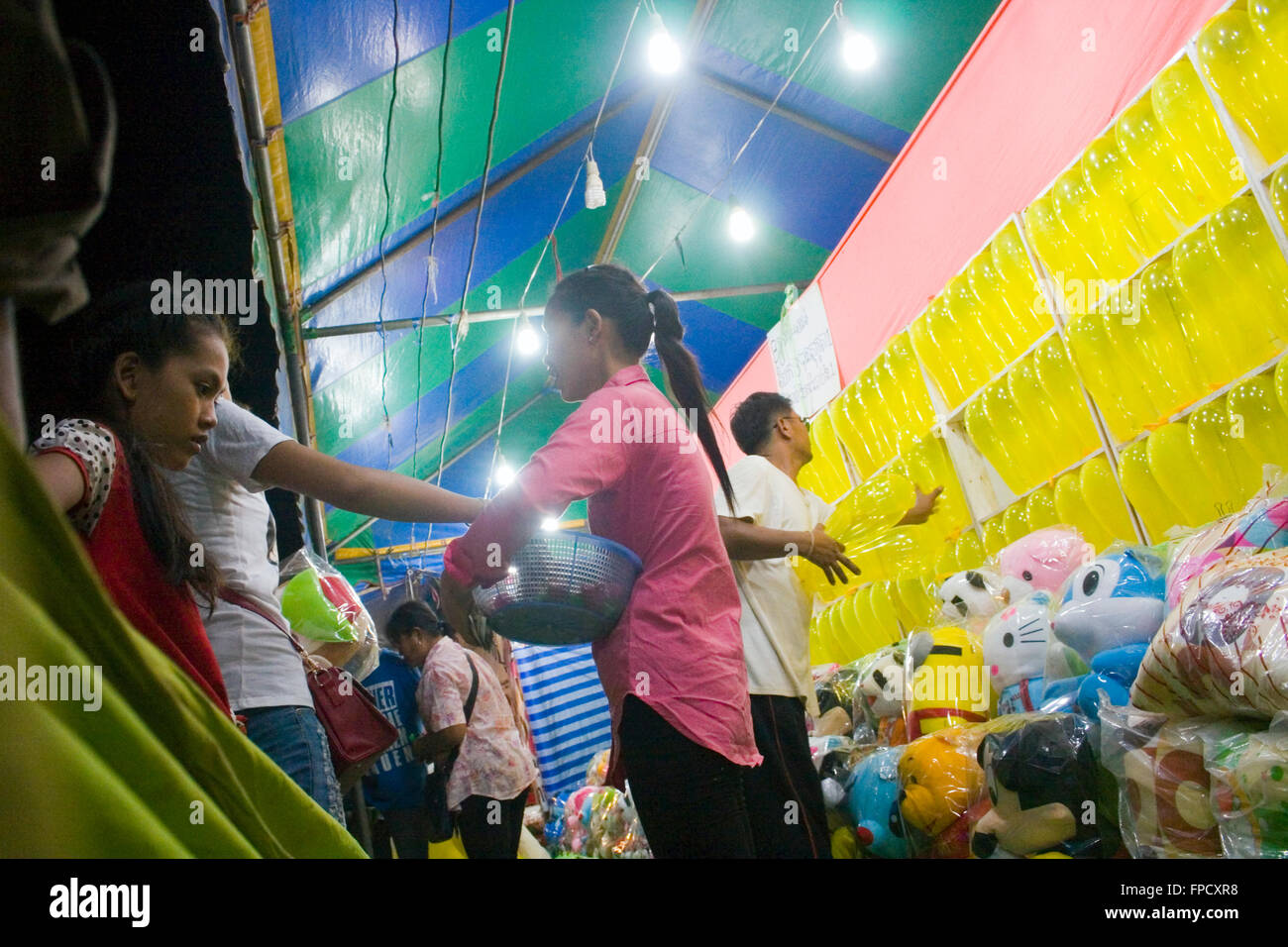 A woman is working at an arcade game where people throw darts at ...