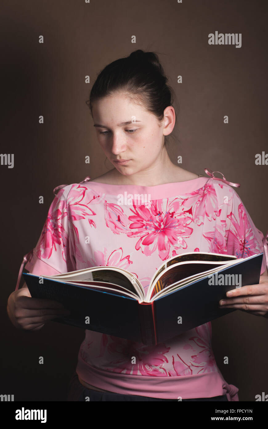young beautiful girl reading a book in hard cover Stock Photo - Alamy
