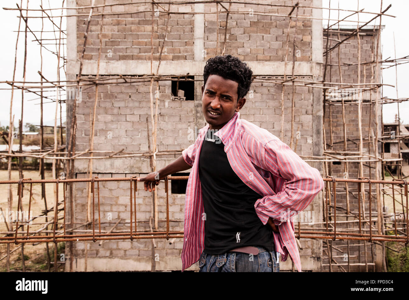 Young man posing in front an under construction concrete brick's ...