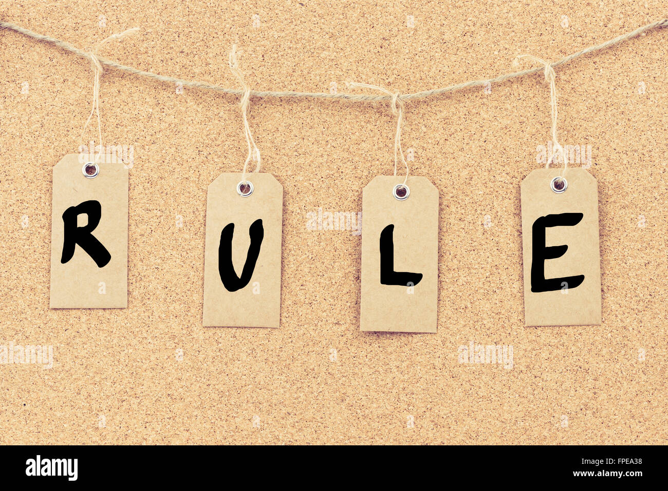 Vintage grunge tags with letters on rope string, word RULE over cork ...