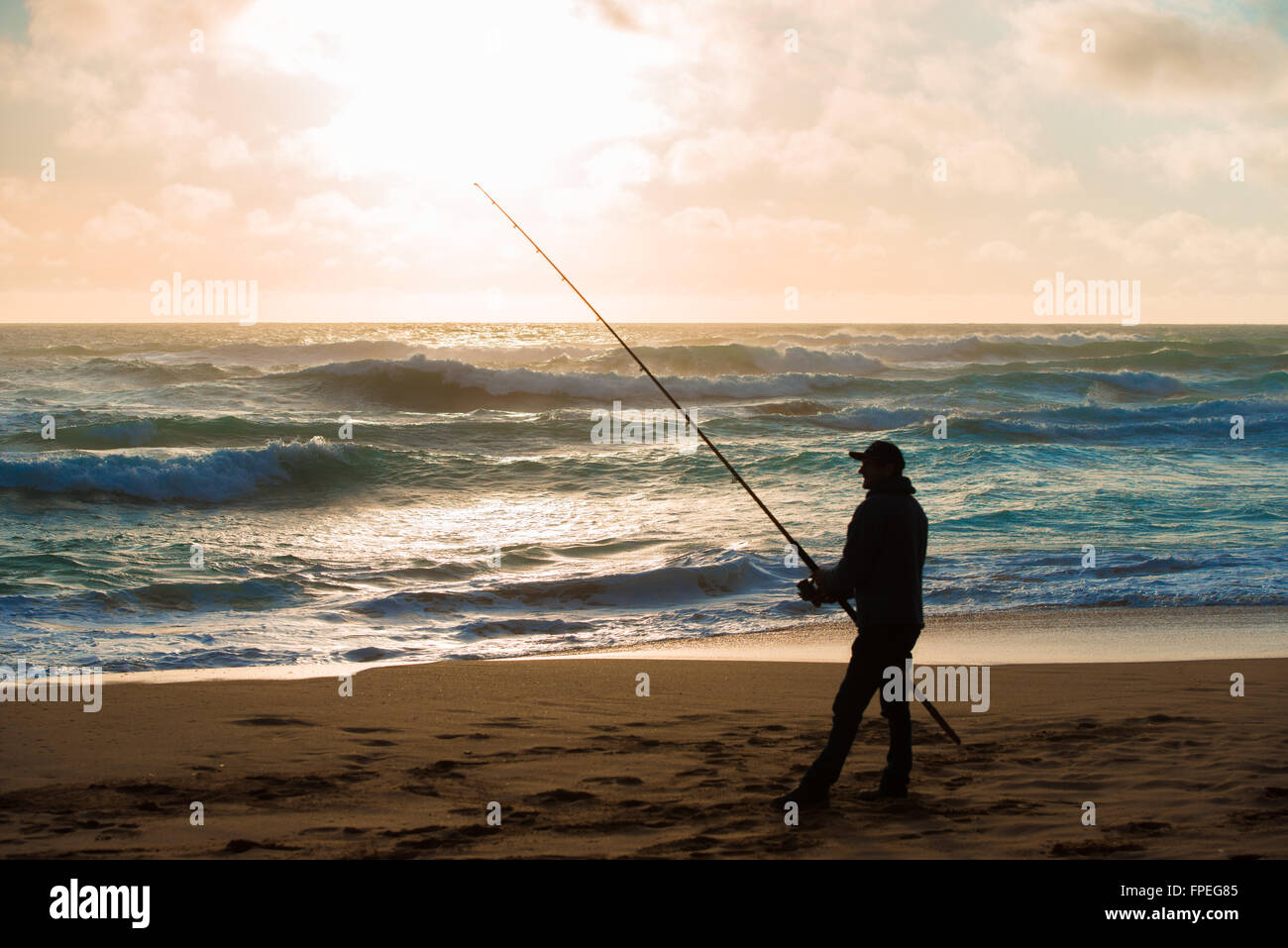 Man fishing on Beach at Sunset Stock Photo - Alamy