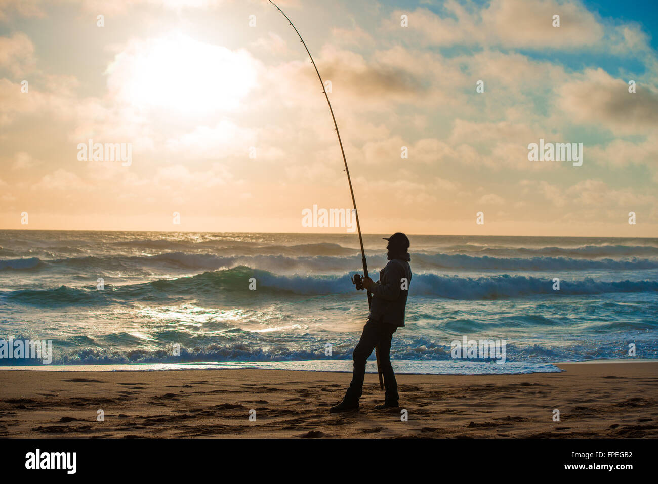 Man fishing on Beach at Sunset Stock Photo - Alamy