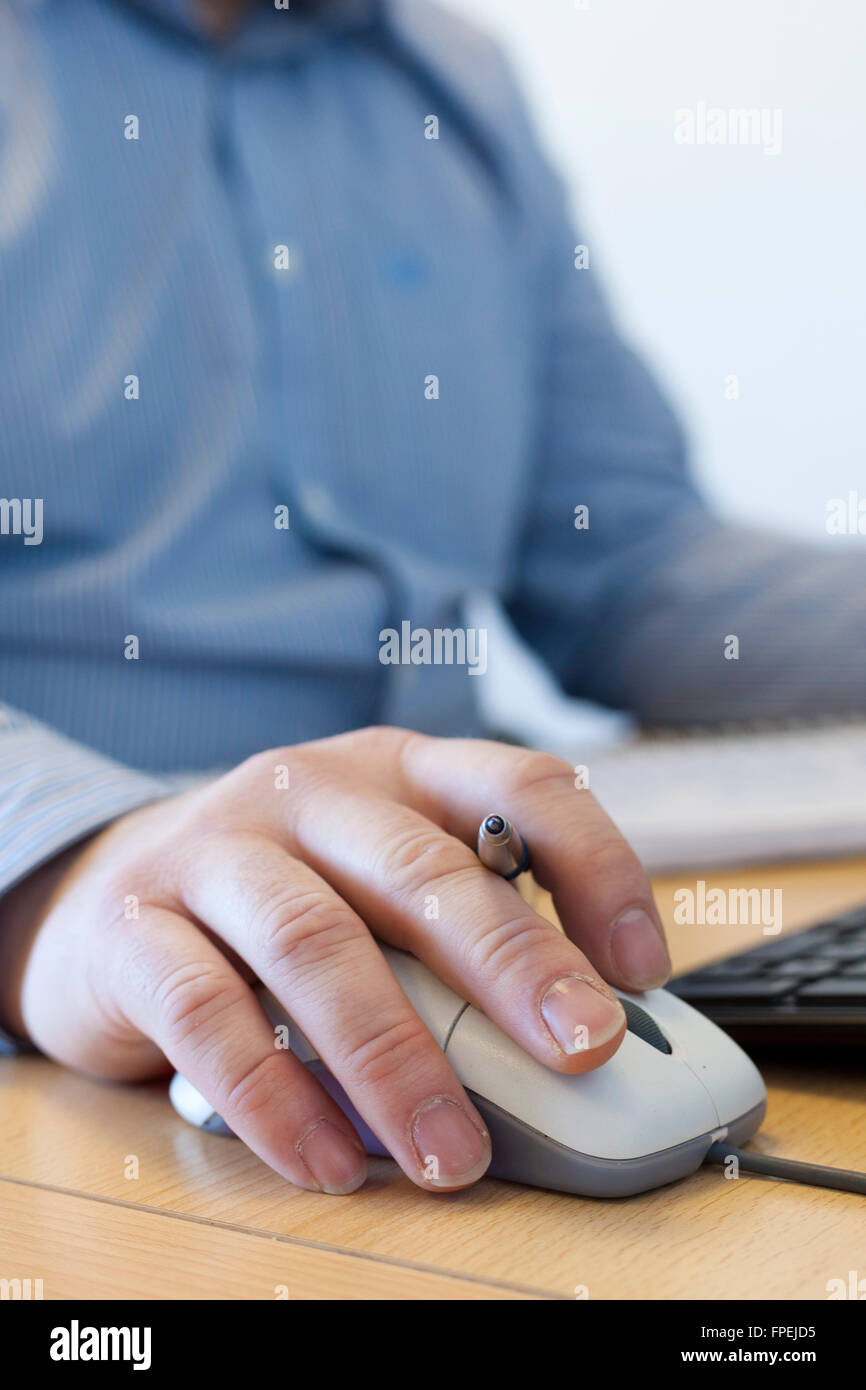 A close up of a male hand holding a mouse with a pen as the man works ...