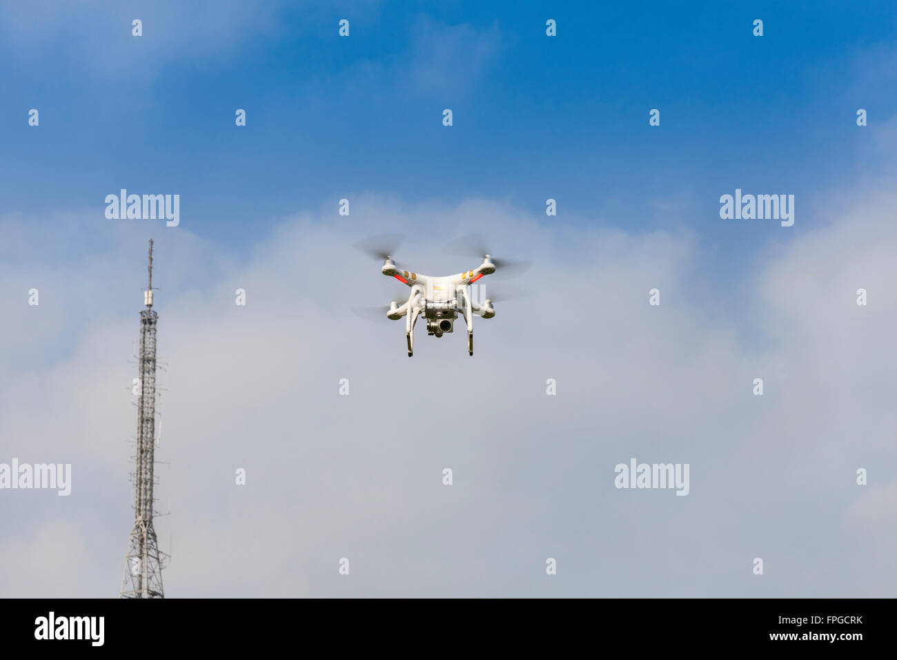 Quadcopter drone in the sky with transmission mast in the background ...