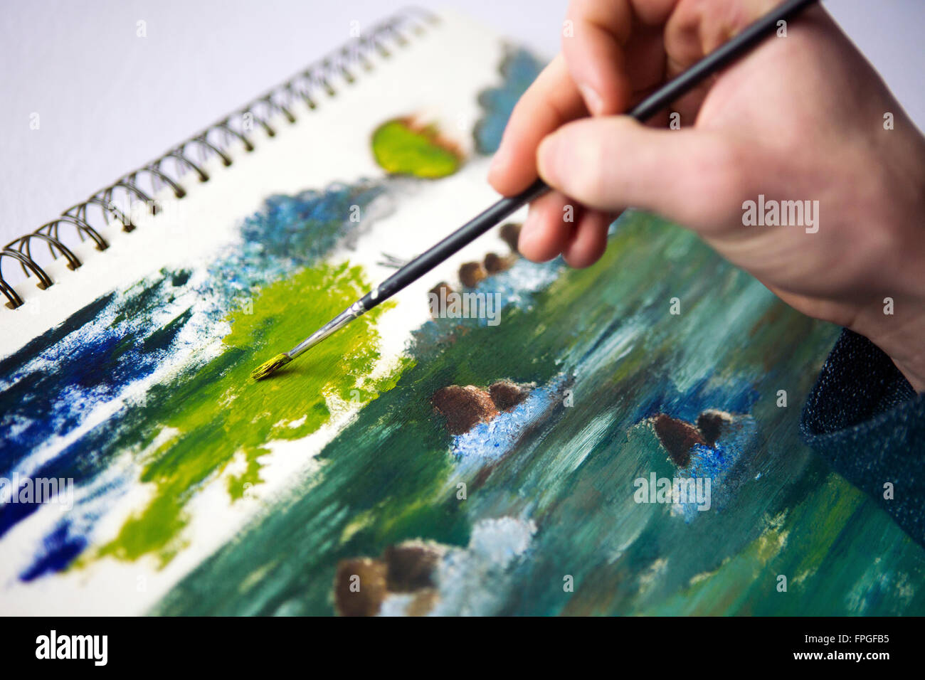 close-up of hand painting a colorful landscape picture Stock Photo - Alamy