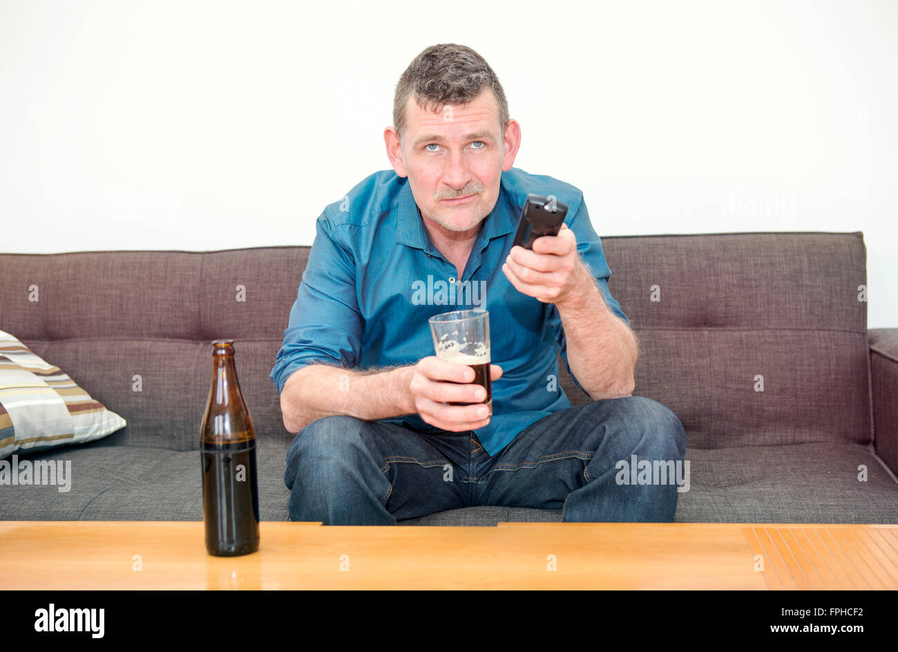 man sitting on couch, drinking beer and watching tv Stock Photo - Alamy