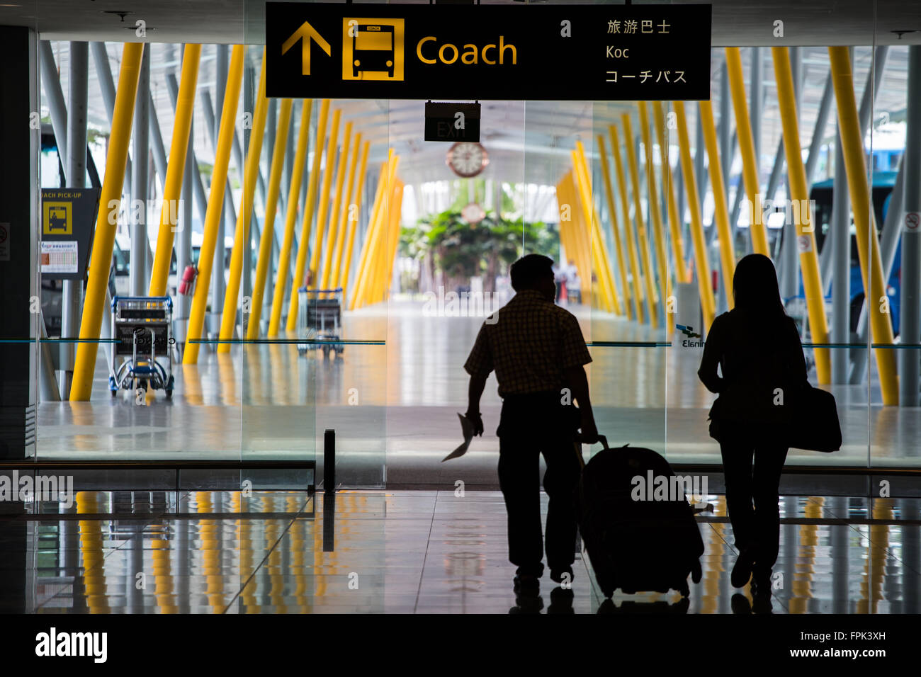 Back view of two travellers in silhouettes are walking towards a coach ...