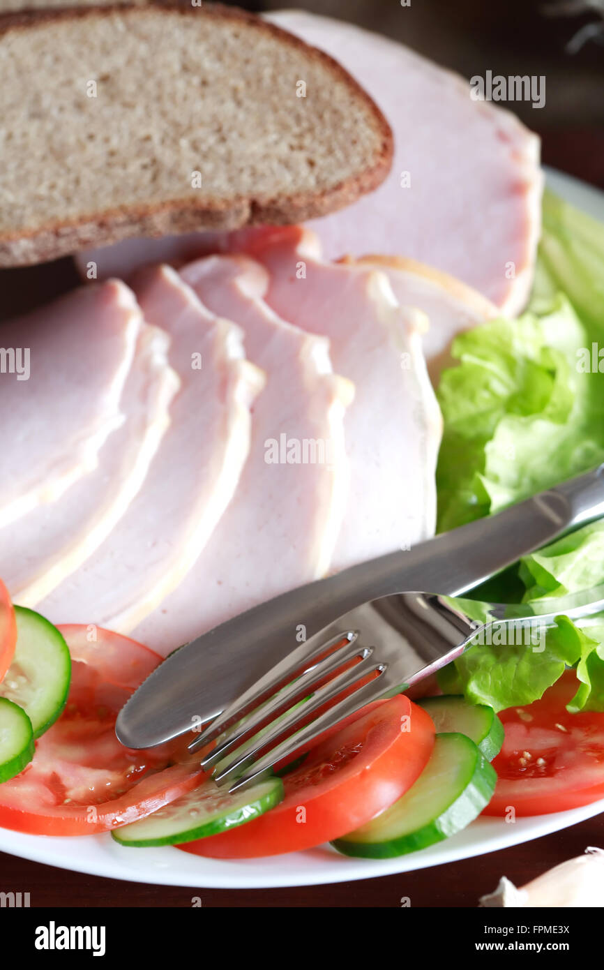 Plate with sliced vegetables and ham near fork and knife Stock Photo ...