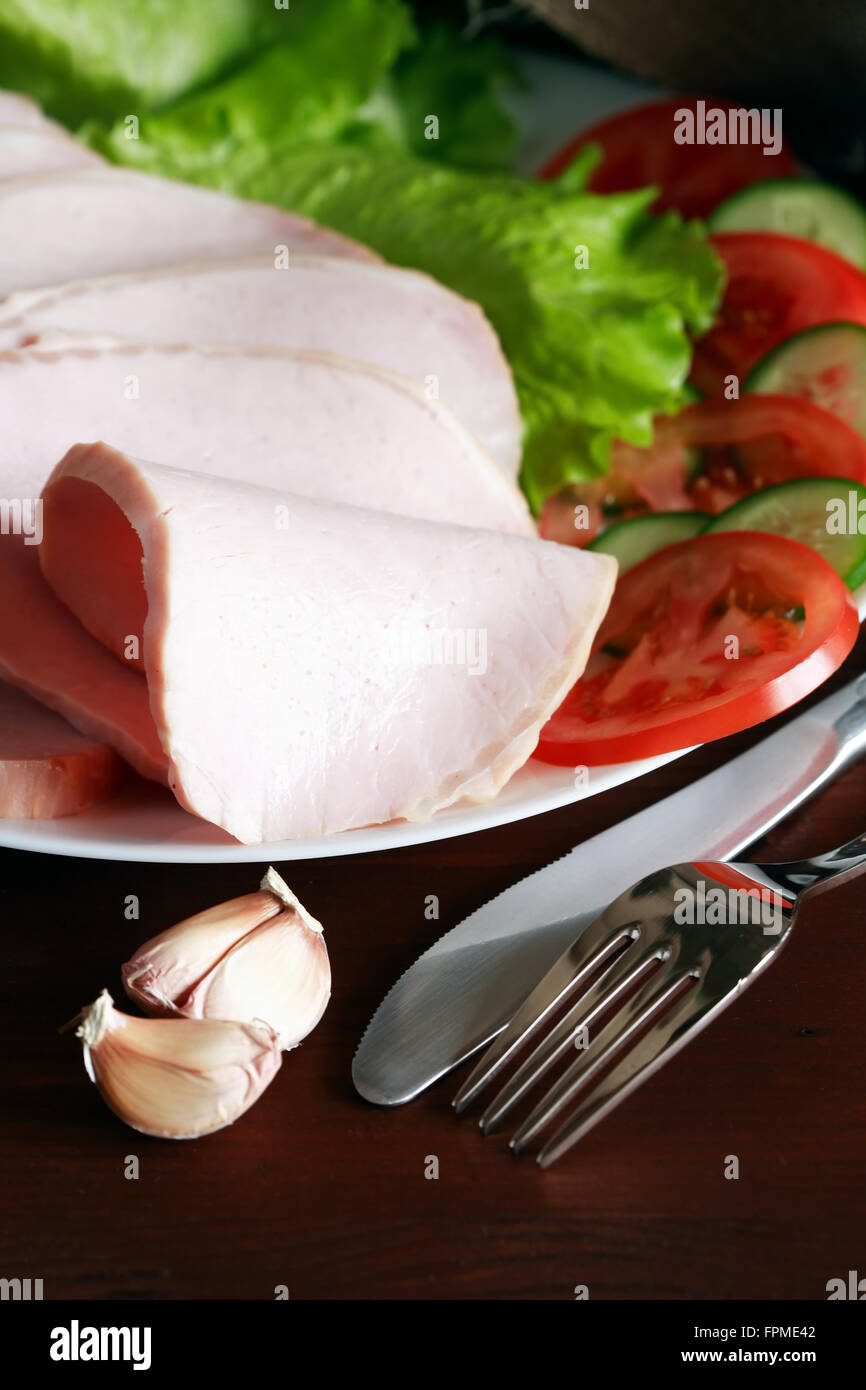 Plate with sliced vegetables and ham near fork and knife Stock Photo ...