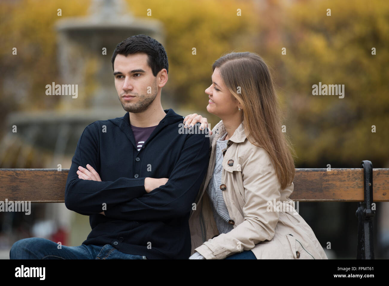 young couple having romantic conversation after love fight on the bench ...